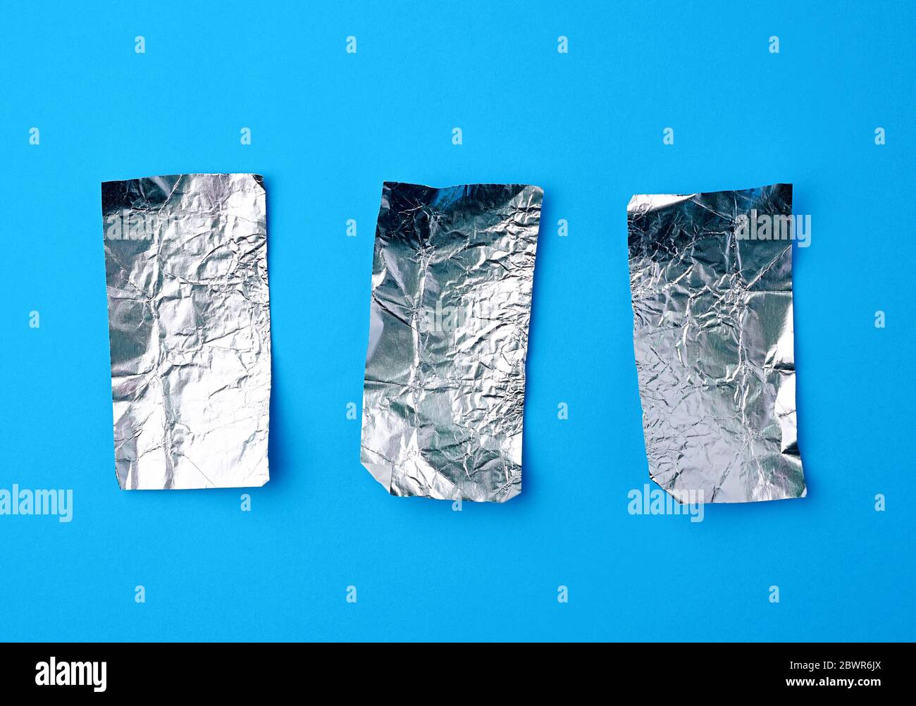 various crumpled foil used candy wrappers on a blue background, top ...