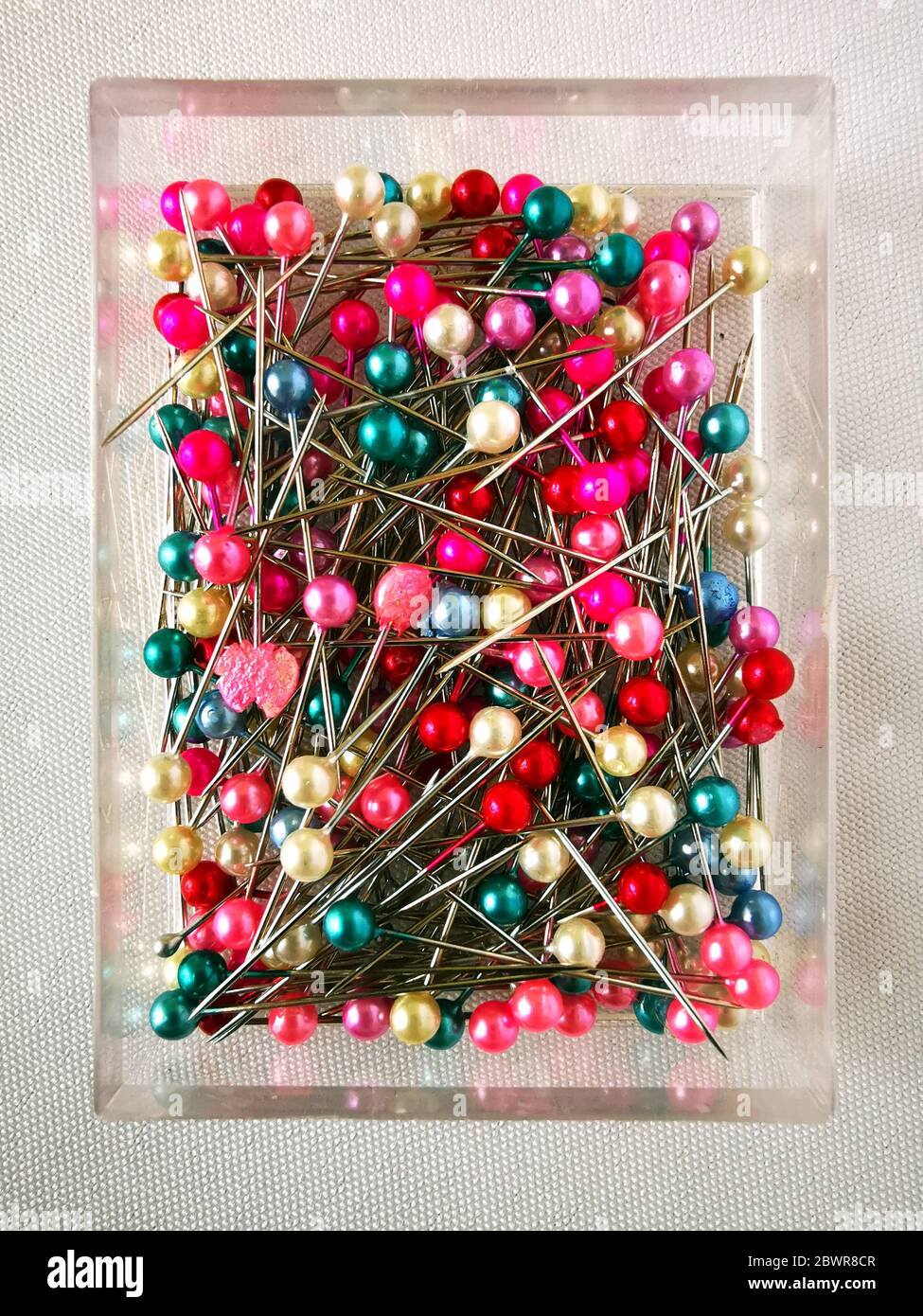 High angle shot of colorful sewing needle pins on a white fabric Stock ...