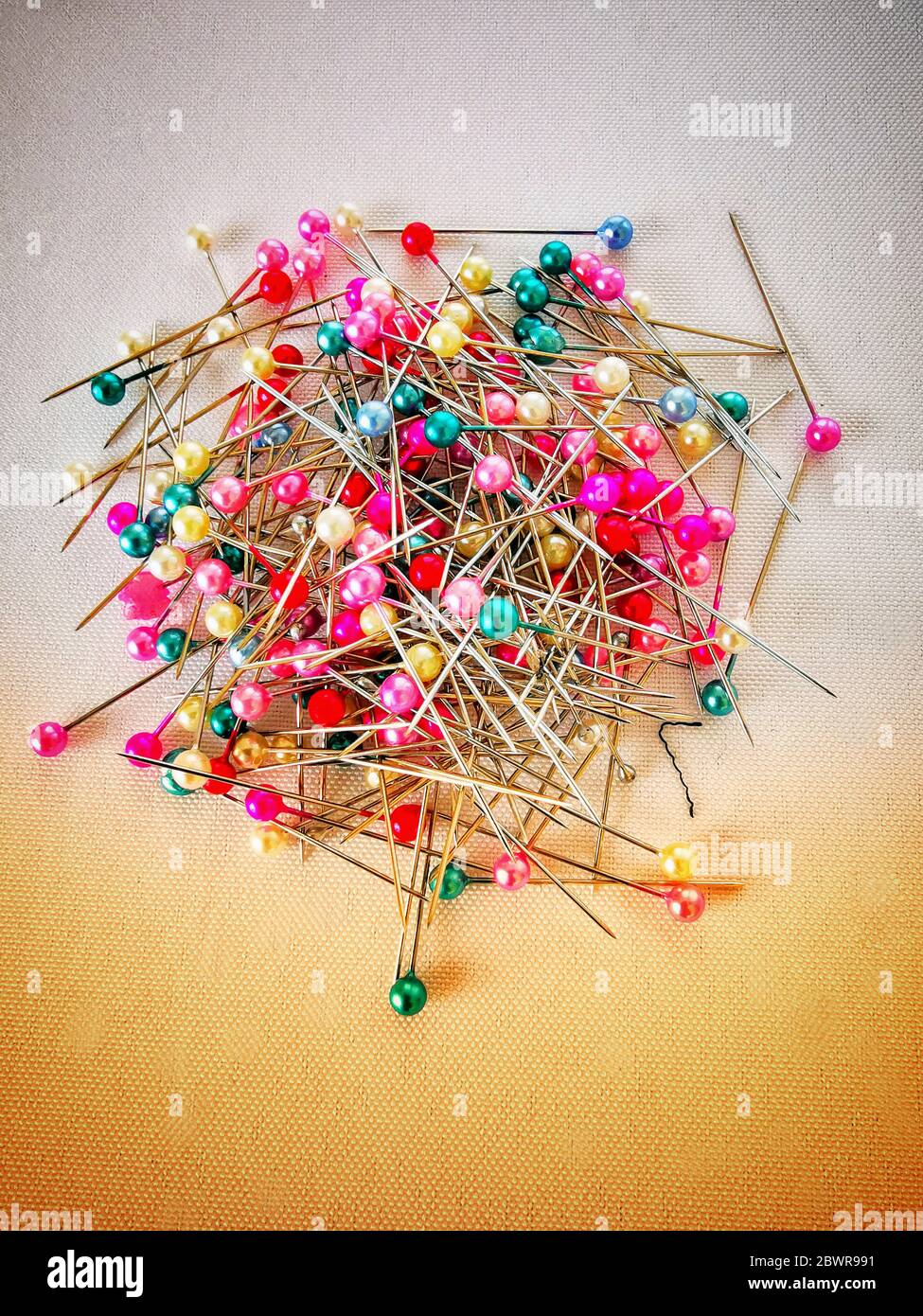 High angle shot of colorful sewing needle pins on a white fabric Stock ...