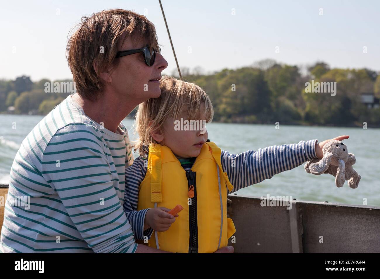 Two year old boy pointing excitedly whilst out on a boat with his ...