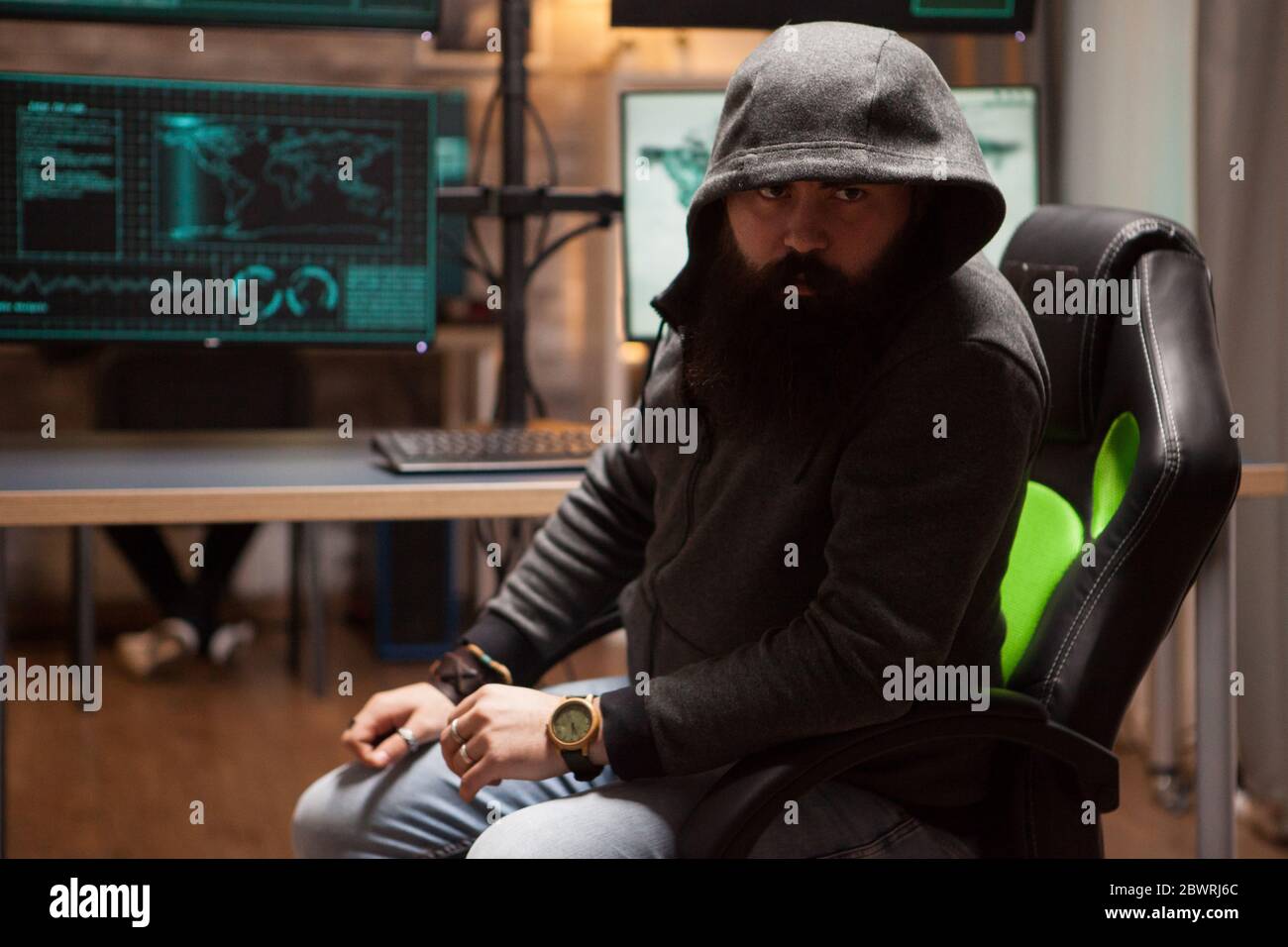 Dangerous bearded hacker wearing a hoodie and looking into the camera ...