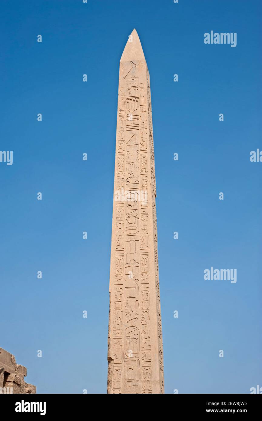 Large tall ancient egyptian obelisk at the temple of Karnak in Luxor with hieroglyphic carvings ...