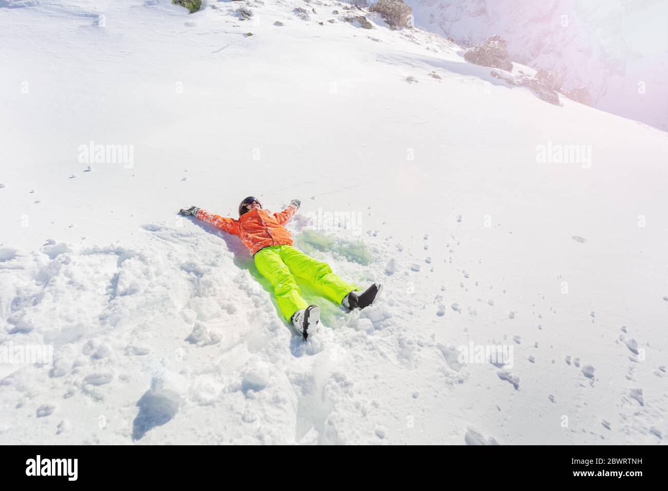 Girl have fun laying in the snow in star shape wearing orange yellow ...