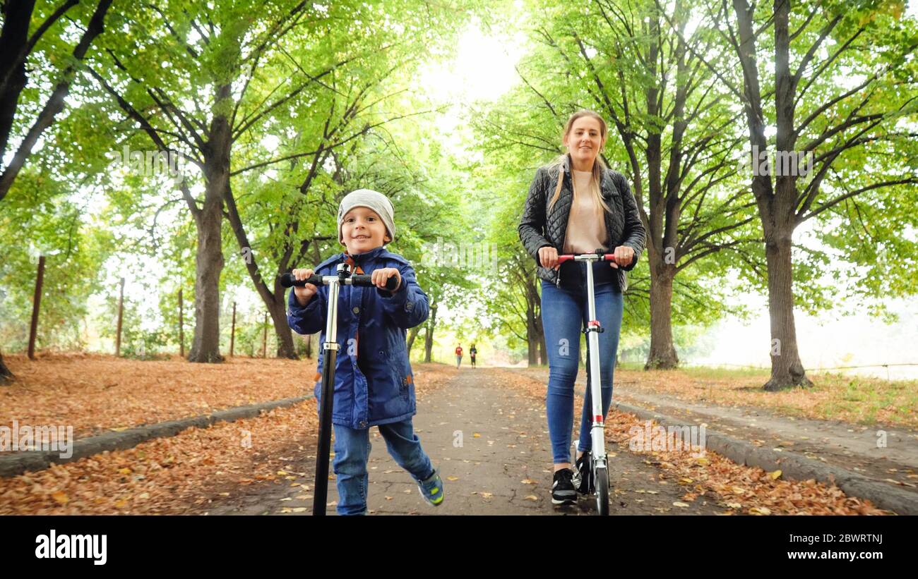 Portrait of smiling little boy enjoys riding on scooters with his ...