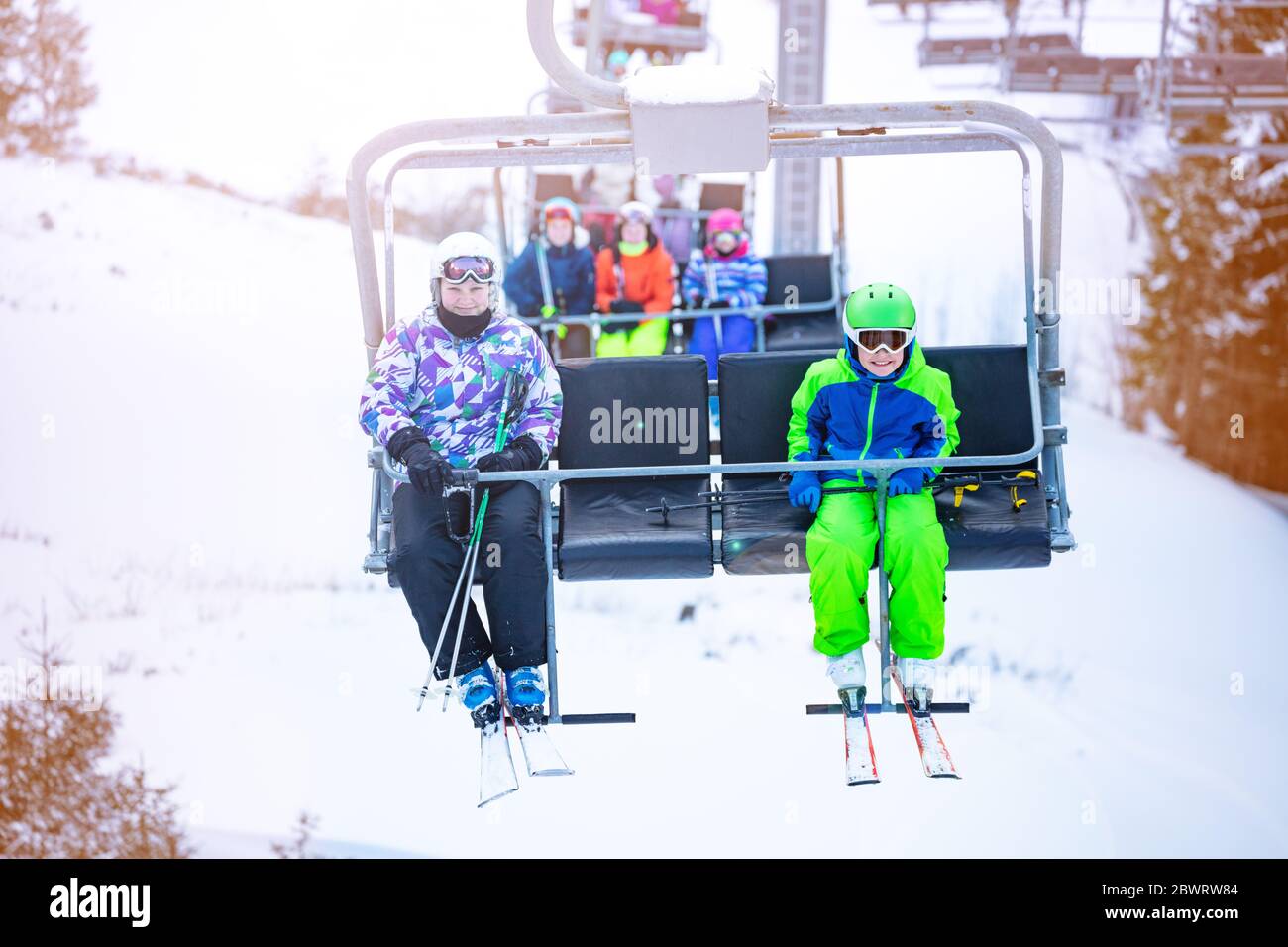 Boy and girl sit on the ski chair lift together on Alpine mountain ...