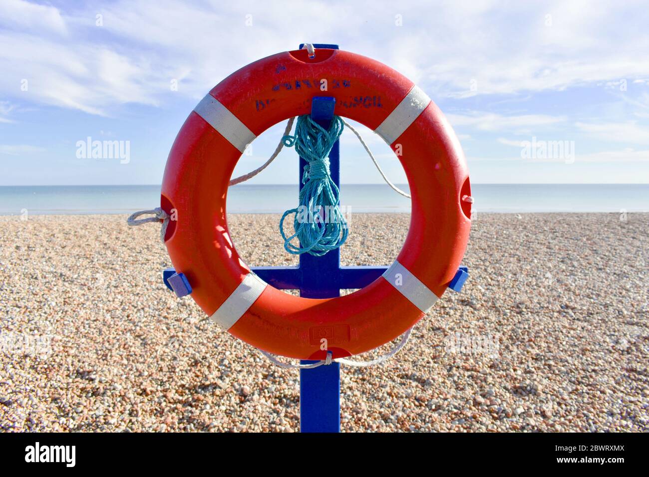 Bright red lifebuoy, on a blue stand by the sea and beach in summer. A ...
