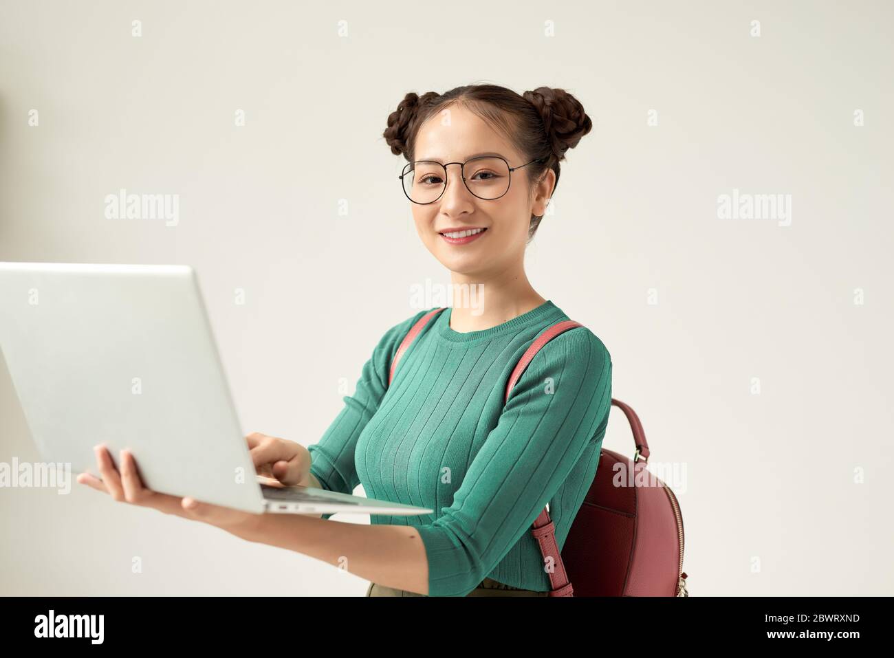 Portrait of a smiling girl holding laptop computer isolated on a white ...