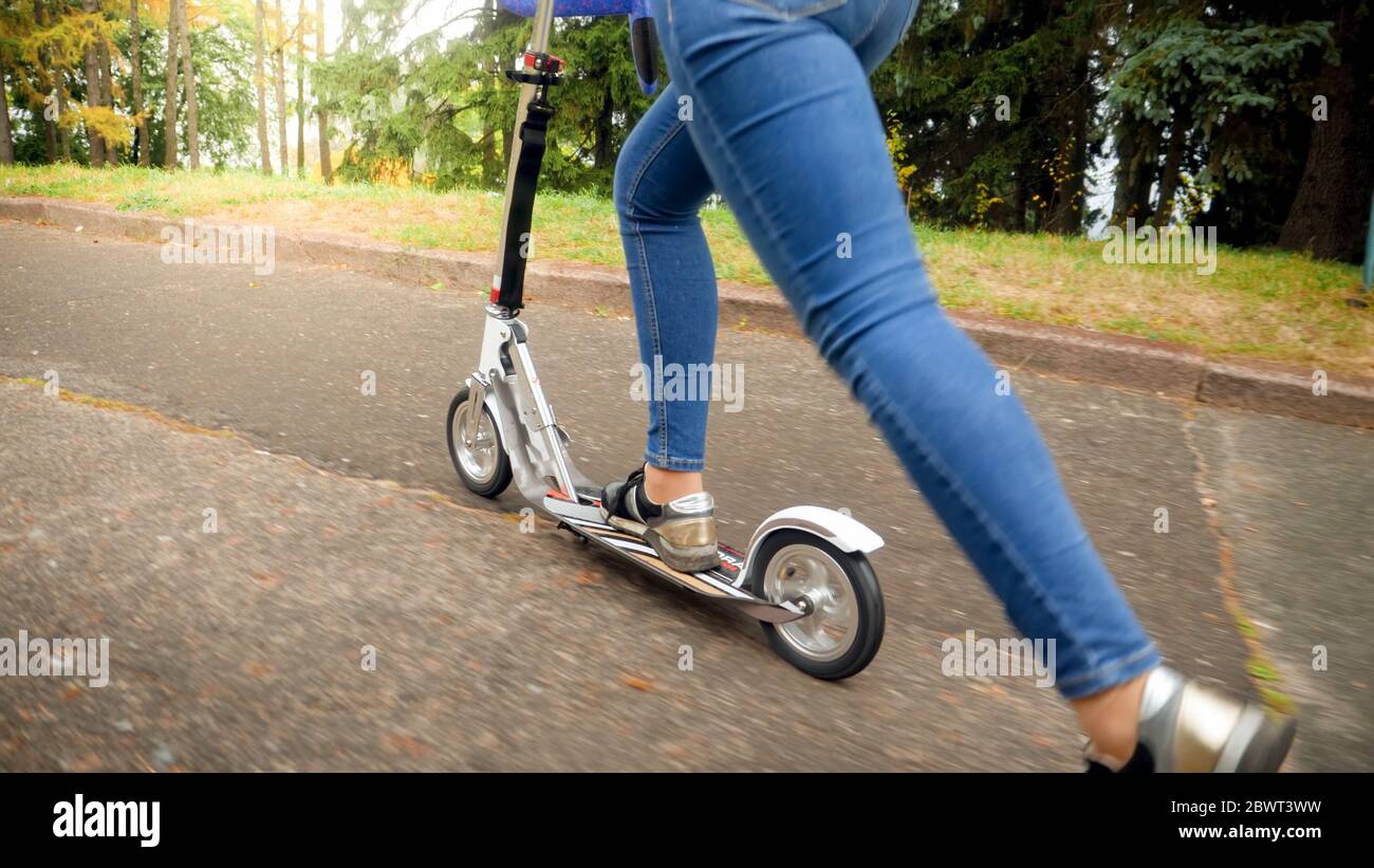 Closeup image of young woman riding fast on kick scooter at park Stock ...