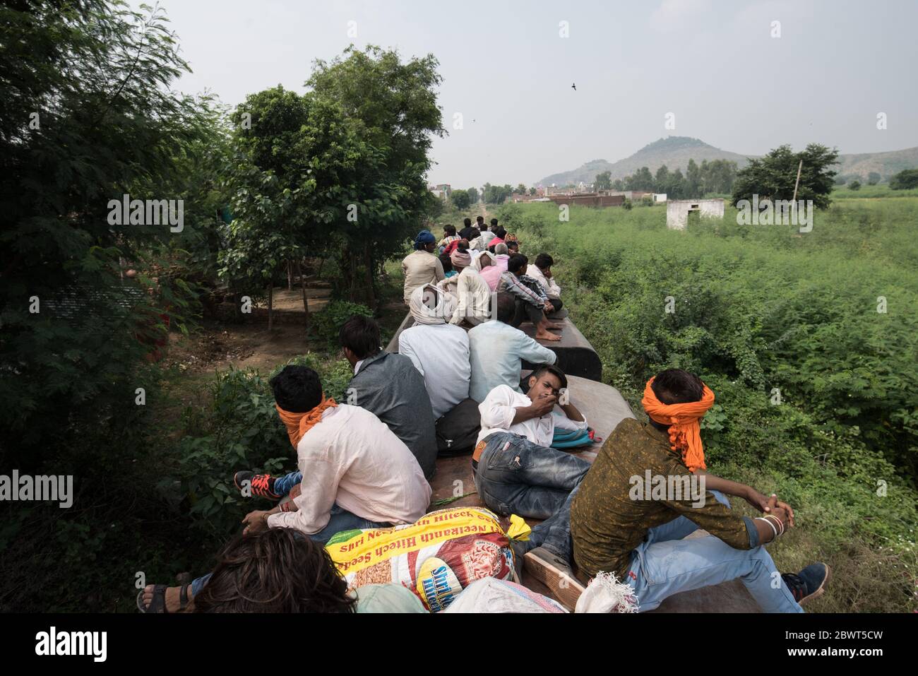 Men on top of overcrowded train passing through countryside in Madhya ...