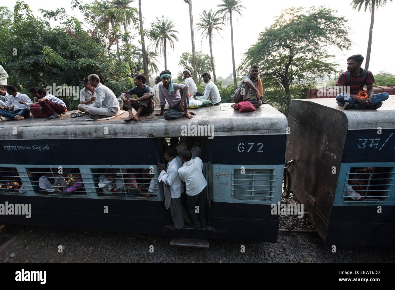 Passengers on top of overcrowded train at a train station in rural ...