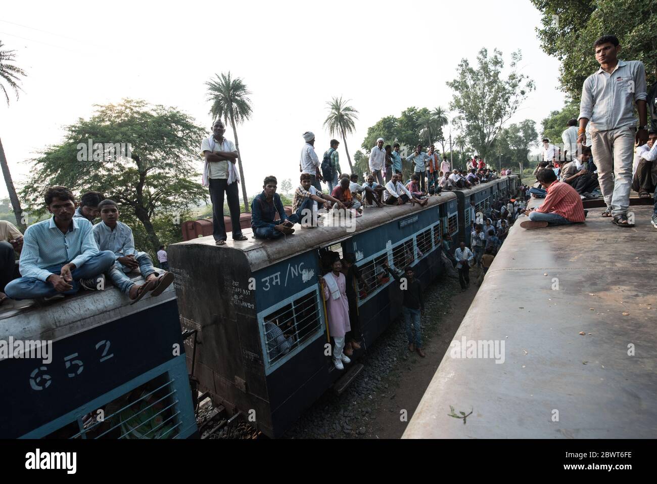 Passengers on top of overcrowded train at a train station in rural ...