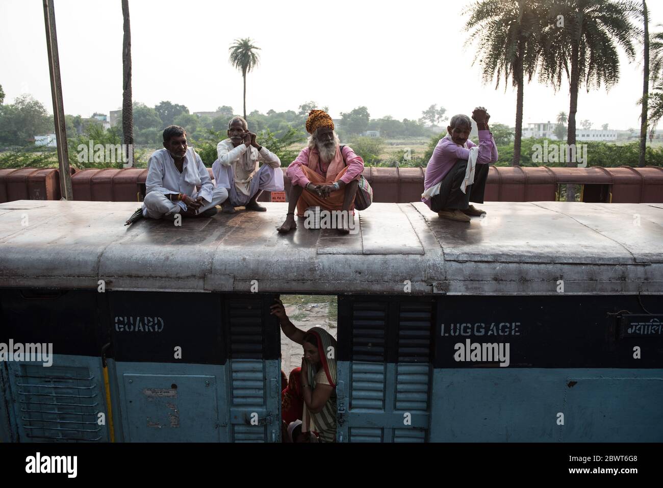 Passengers on top of overcrowded train at a train station in rural ...