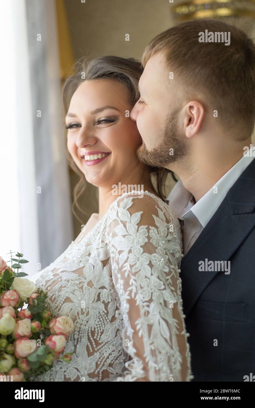 portrait of a happy bride and groom. The groom kisses the bride ...