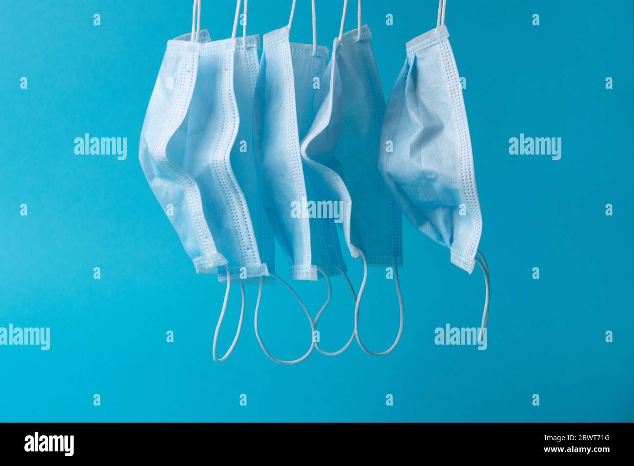 surgical masks hanging in quarantine resting on blue background Stock ...