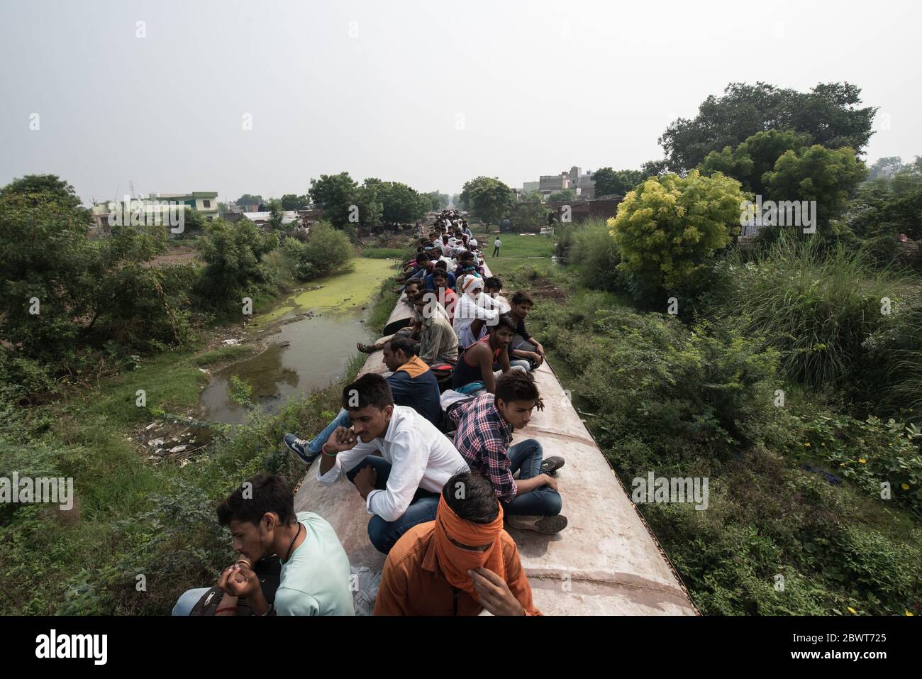Men on top of overcrowded train passing through countryside in Madhya ...