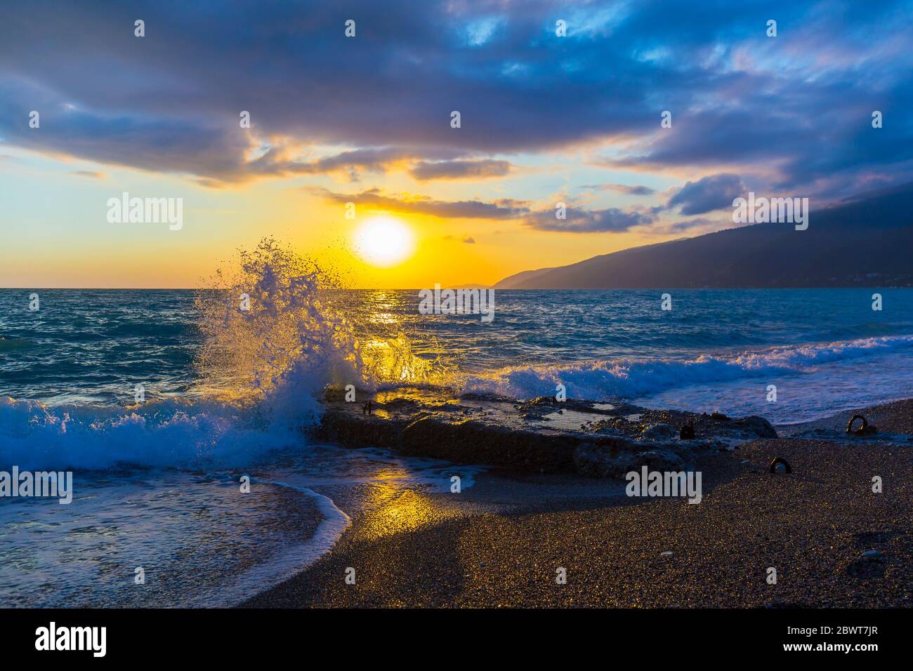 Beautiful shoreline scene with waves at sunset beams Stock Photo - Alamy