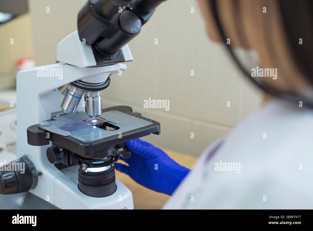 Scientist conducting research taking notes whilst looking through ...