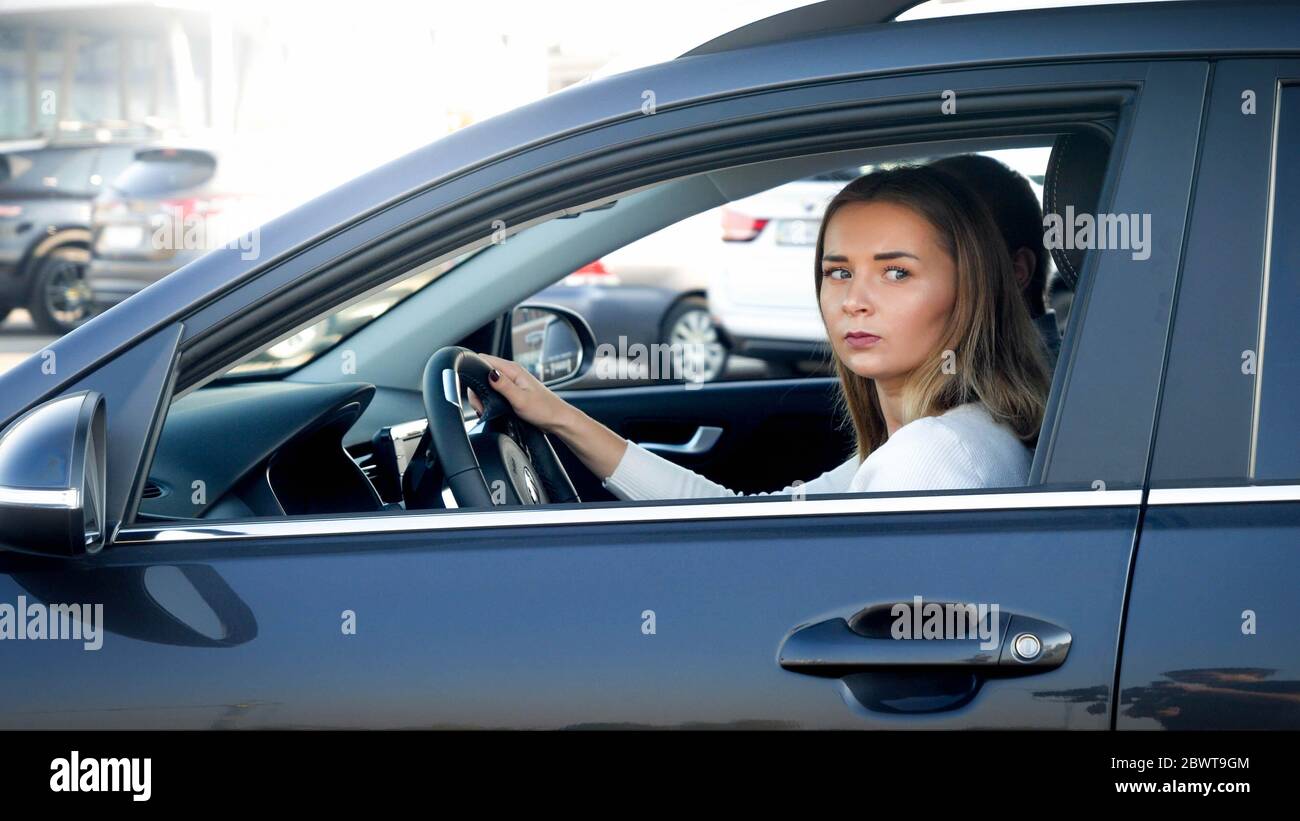 Portrait of young female driver looking out the open window while ...
