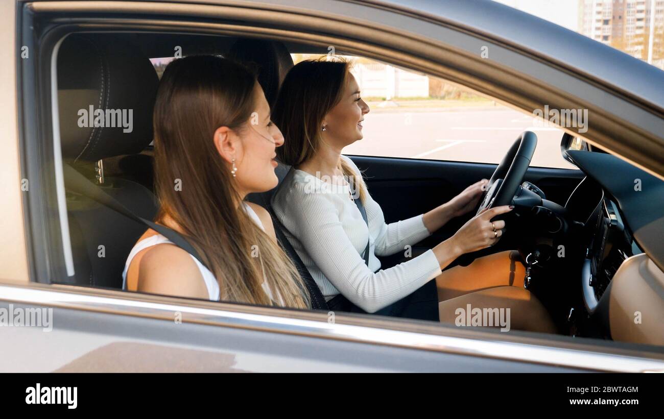 Two happy smiling girls driving a car on city street Stock Photo - Alamy