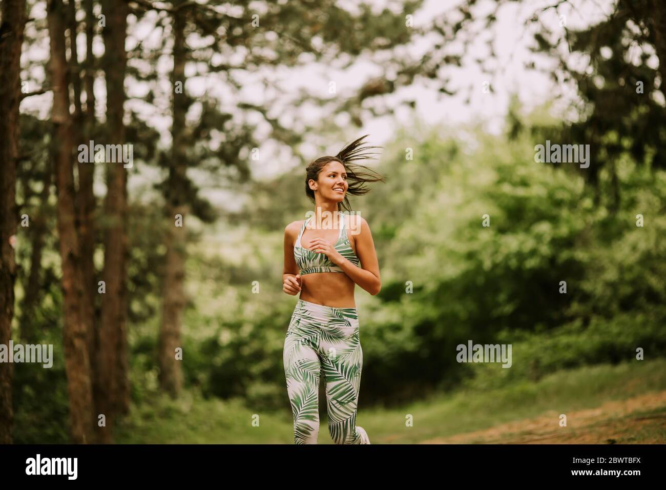 Pretty young fitness woman running at the forest trail Stock Photo - Alamy