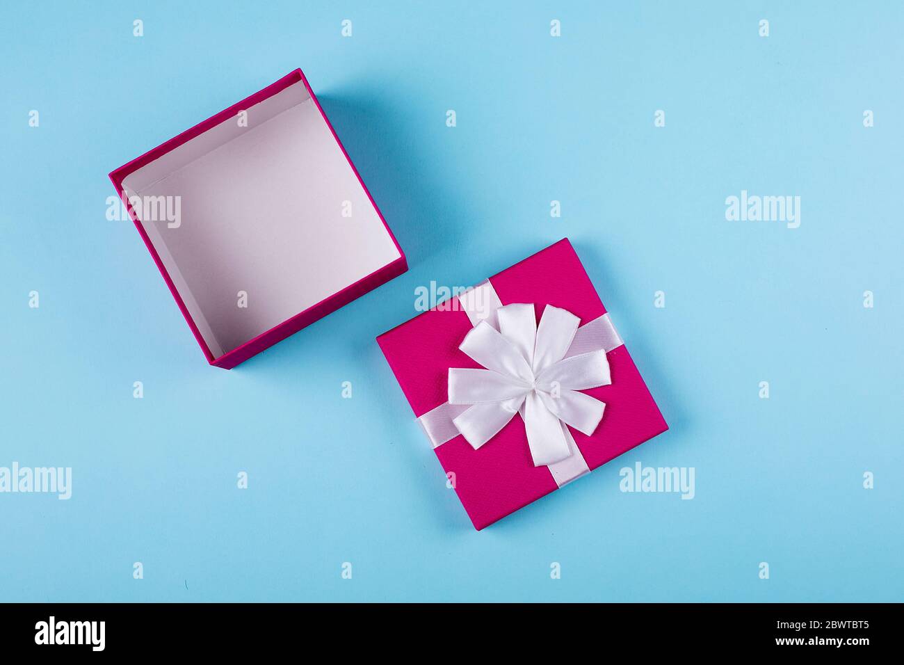 Open pink gift box on blue paper background. Top view, flat lay, place ...