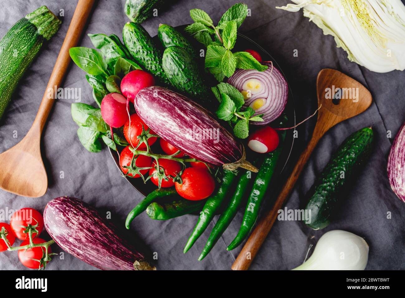 Different fresh colorful vegetables in a plate on a table, flat lay ...