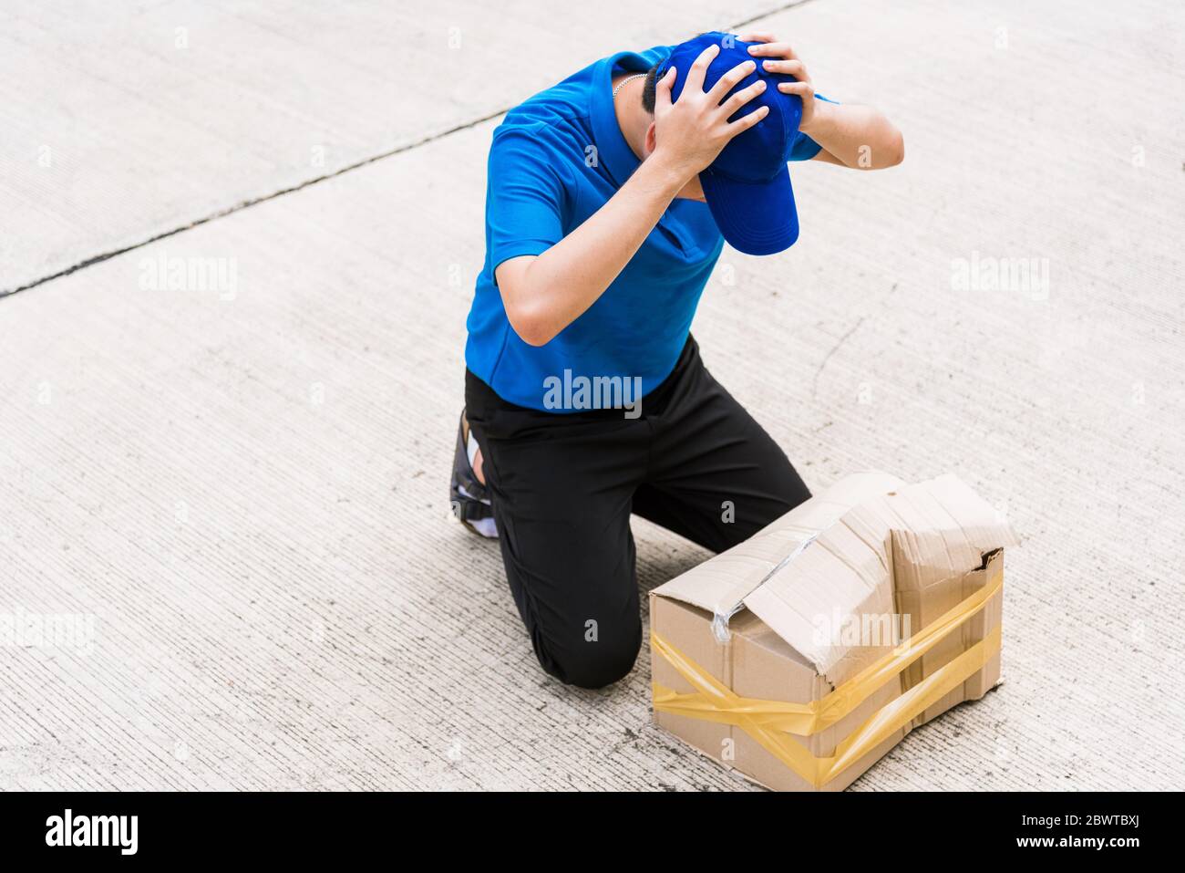Asian young delivery man in blue uniform he emotional falling courier ...