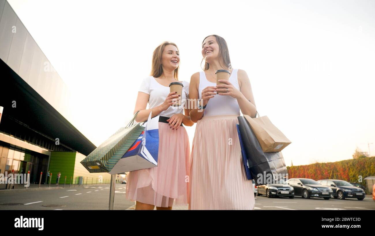 Portrait of two female shopaholics with lots of paper shopping bags ...