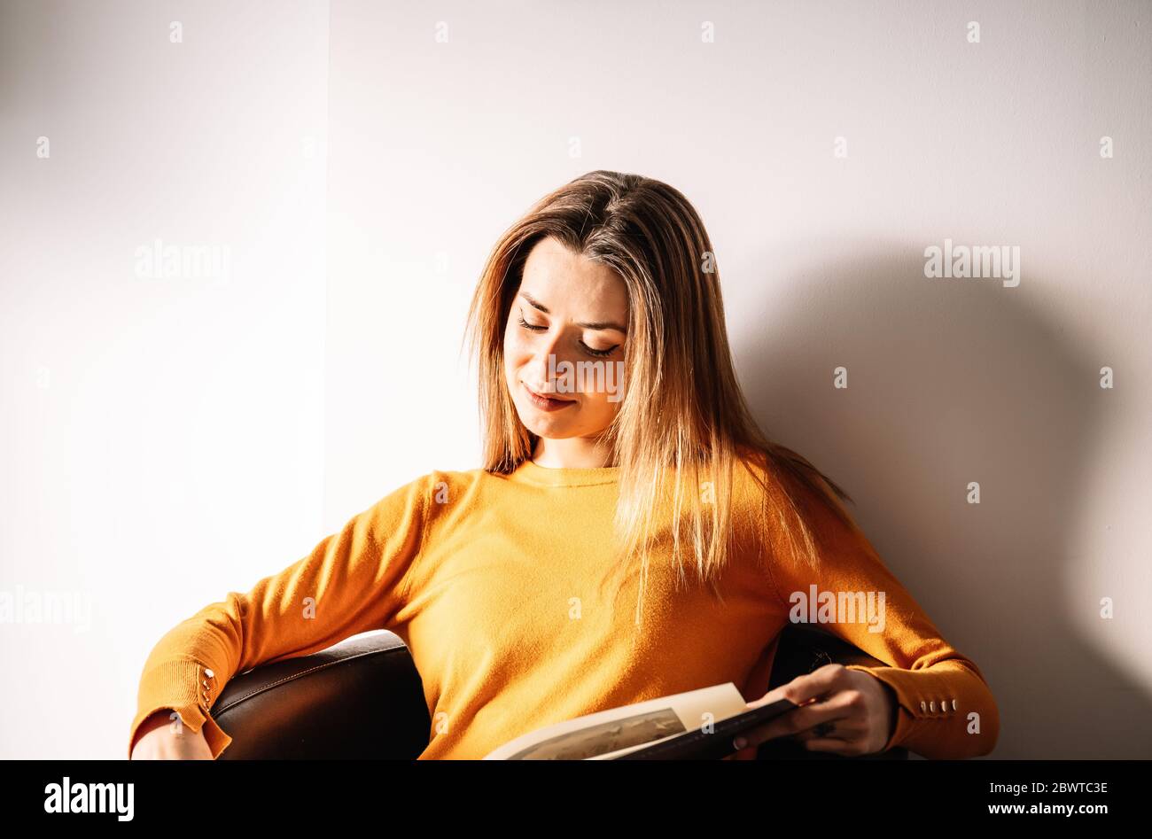 Young female patient smiling and reading magazine while sitting in ...