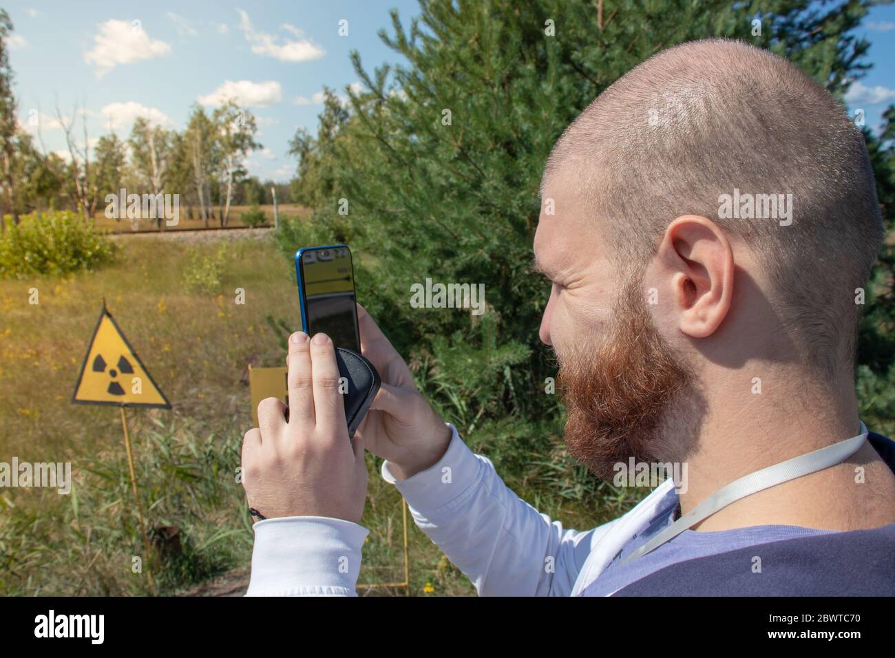 Adult bald man tourist in Chernobyl exclusion zone holding a smartphone ...