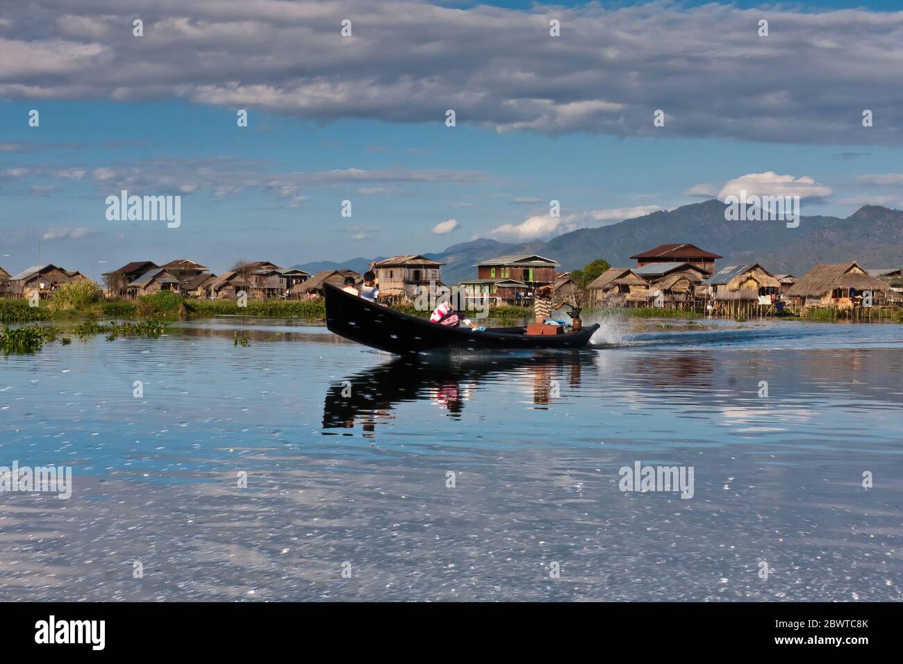 A family of Intha people in the traditional long motorboat sailing on ...