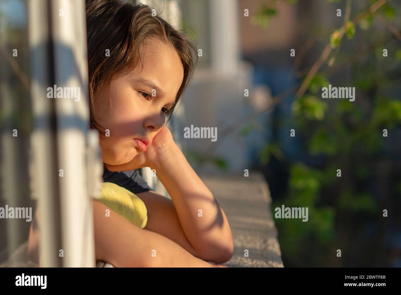 Close up of portrait upset little girl look far in window thinking ...