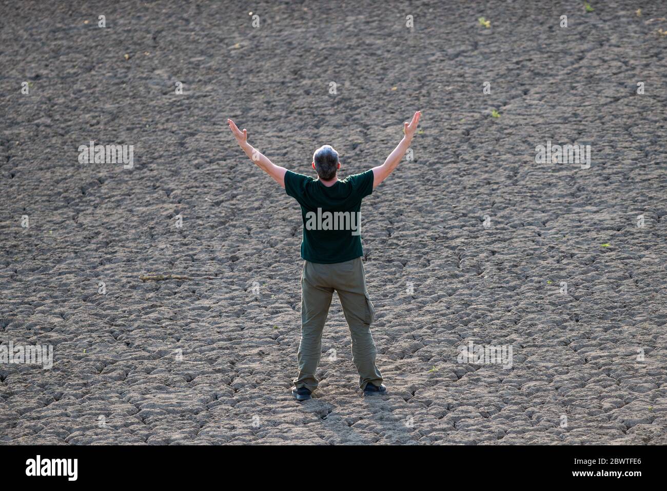 Man raise his hands and praying for rain in dry land Stock Photo - Alamy