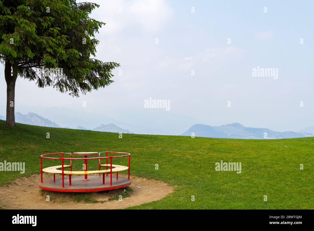 A red roundabout on the grass green of a mountain Stock Photo - Alamy