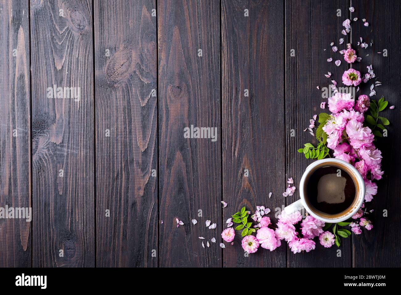 Floral frame consists of pink flowers with coffee cup on wooden ...