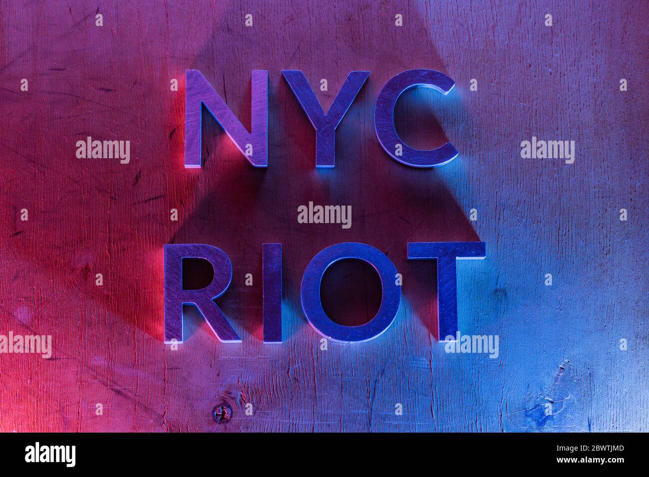 The words NYC riot laid with metal letters on flat plywood surface ...