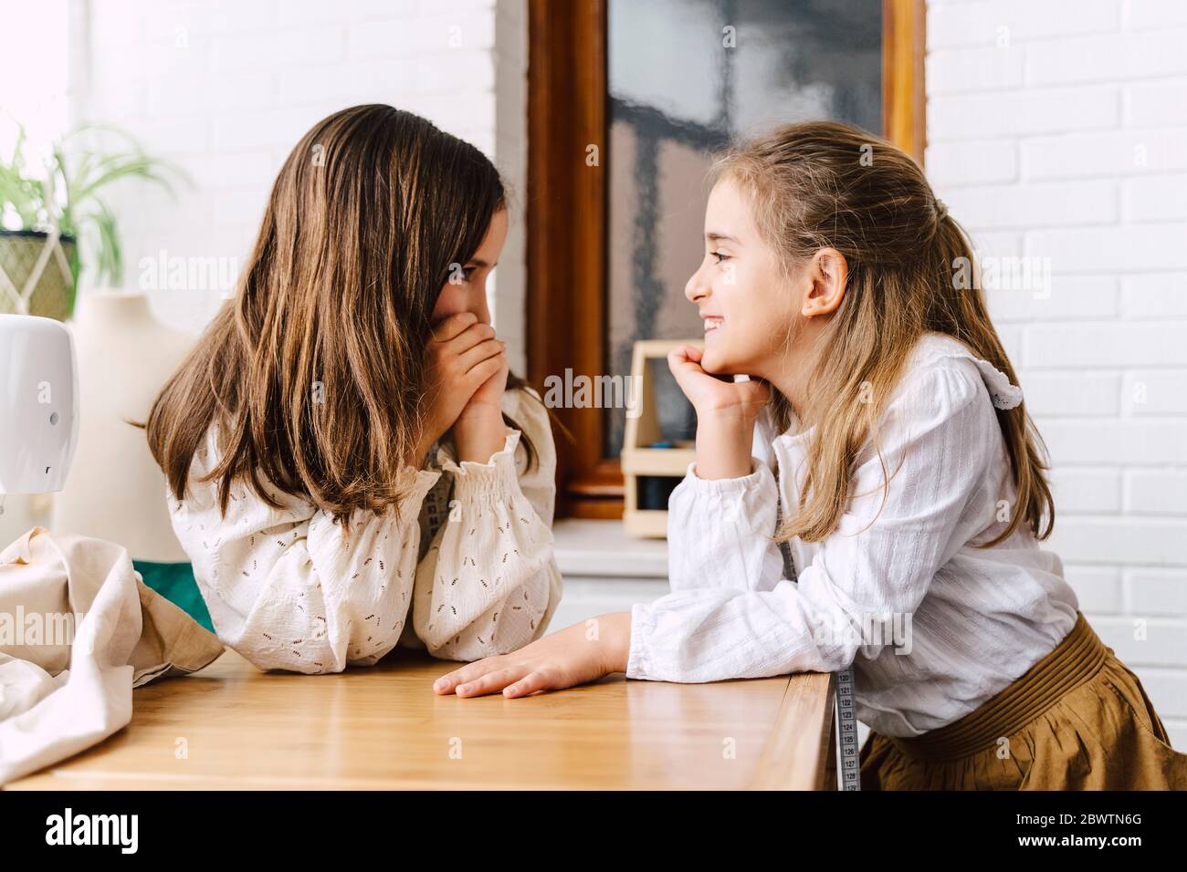 Two girls at table smiling at each other Stock Photo - Alamy