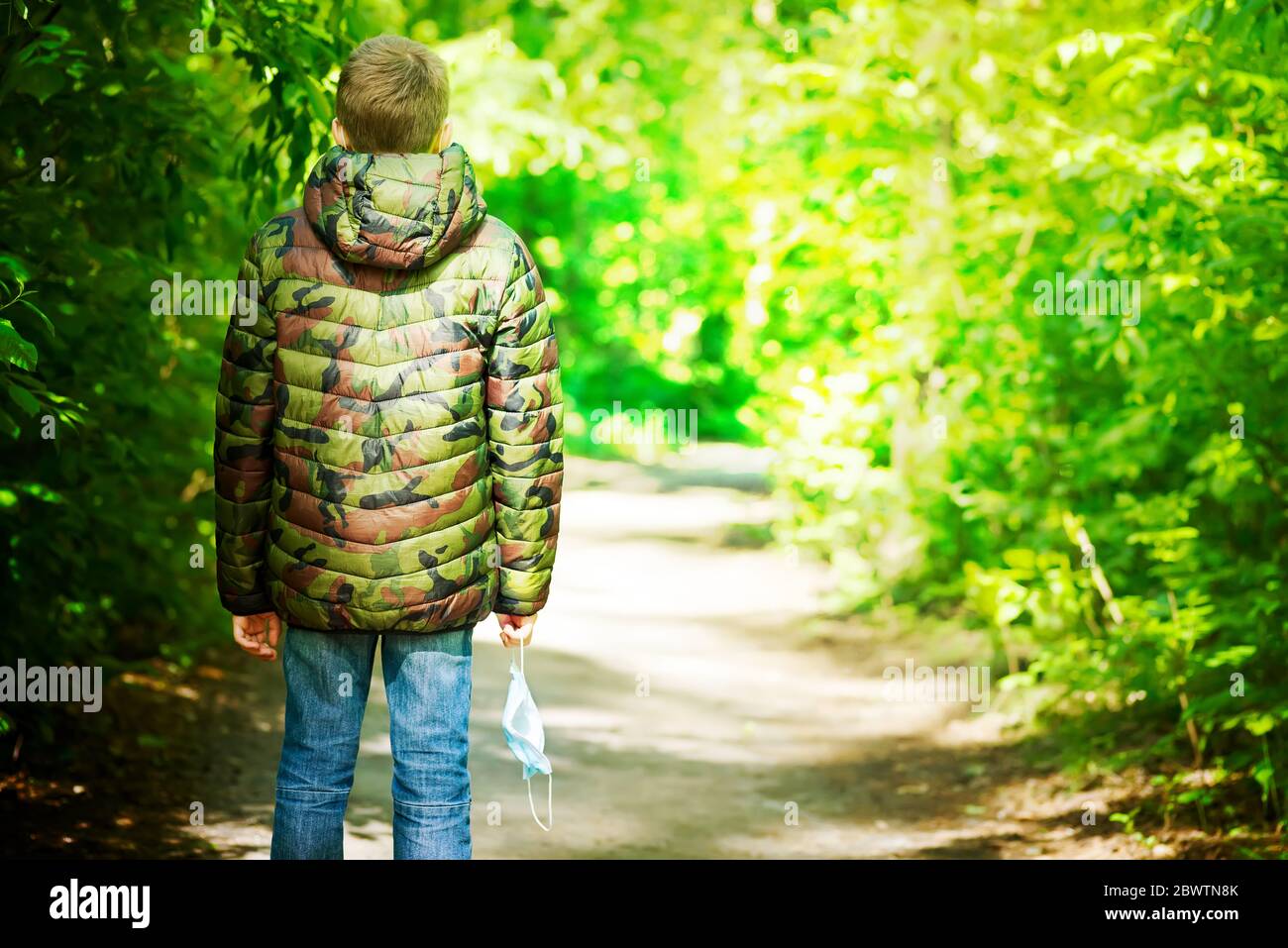 Green park landscape with alone boy, teenager wearing in a jacket with ...