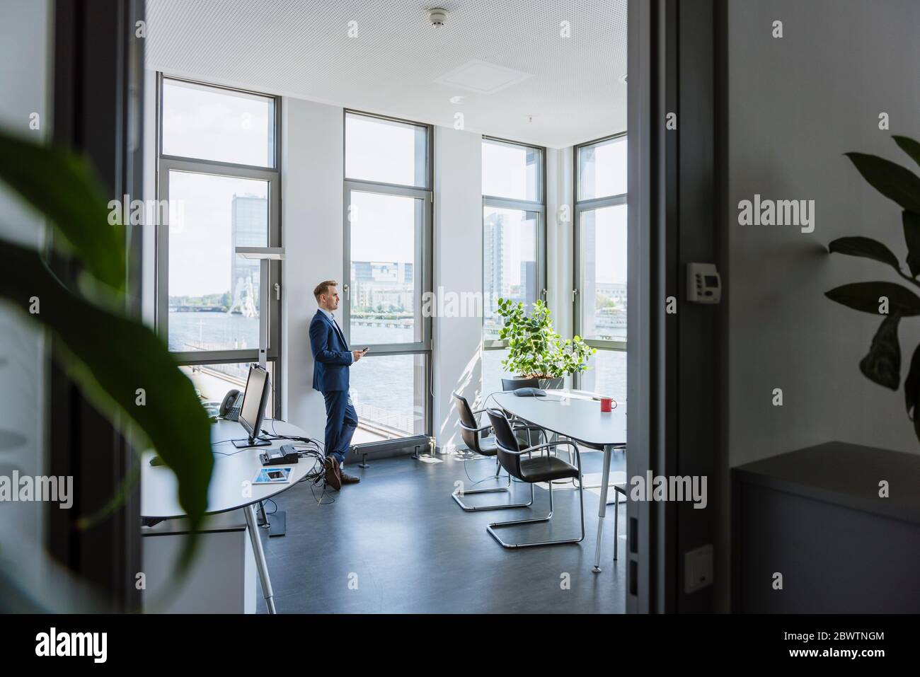 Businessman standing at thw window in office Stock Photo - Alamy