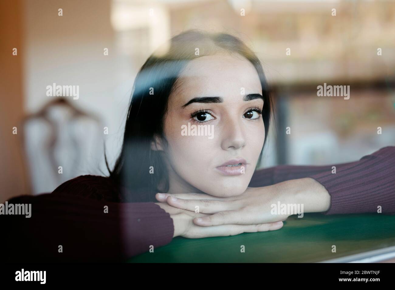 Portrait of young woman behind windowpane Stock Photo - Alamy