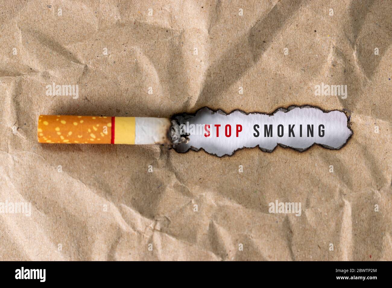 Cigarette burning the brown paper with text STOP. Stop smoking and ...