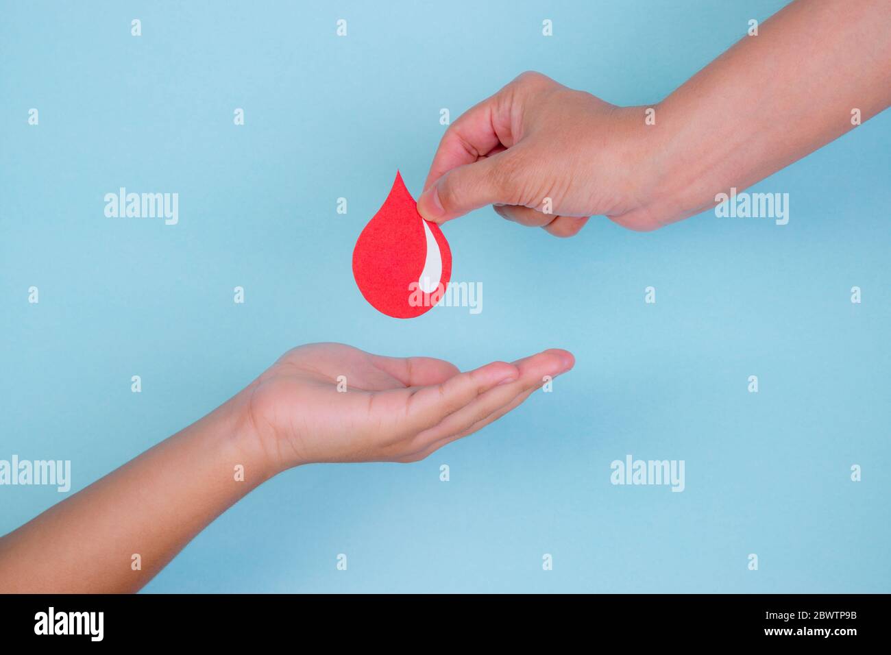 Woman hand gives a red blood drop to a boy hand for blood donation ...