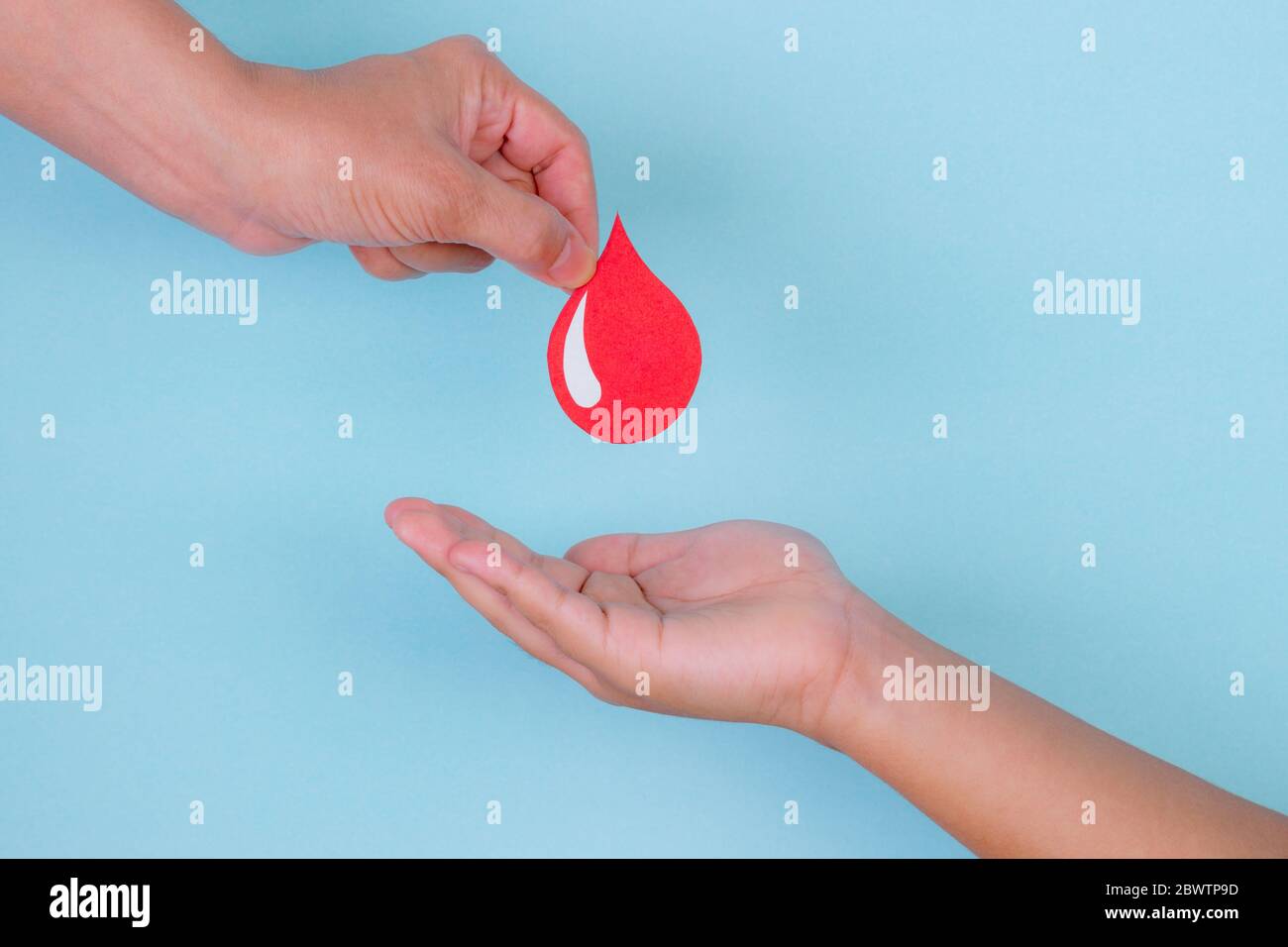 Woman hand gives a red blood drop to a boy hand for blood donation ...