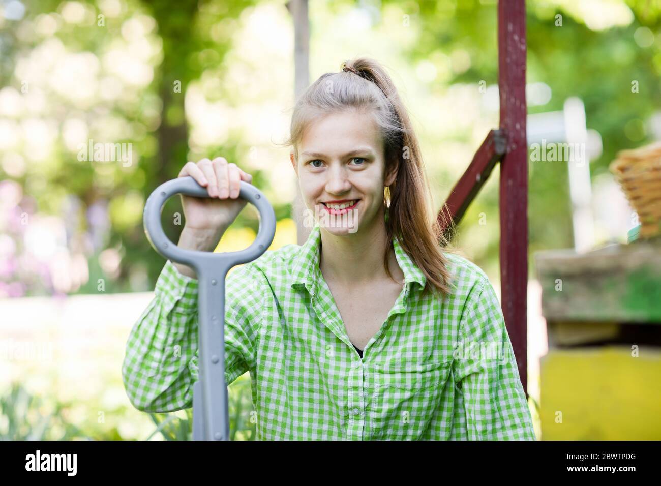 Young woman standing in urban garden, holding shovel Stock Photo - Alamy