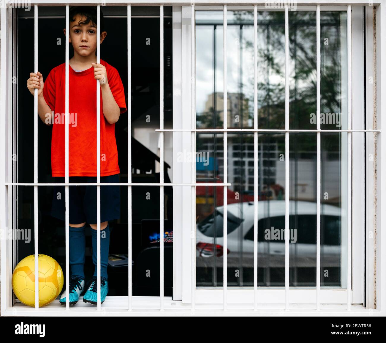 Boy with soccer ball at open window looking through window grate Stock ...