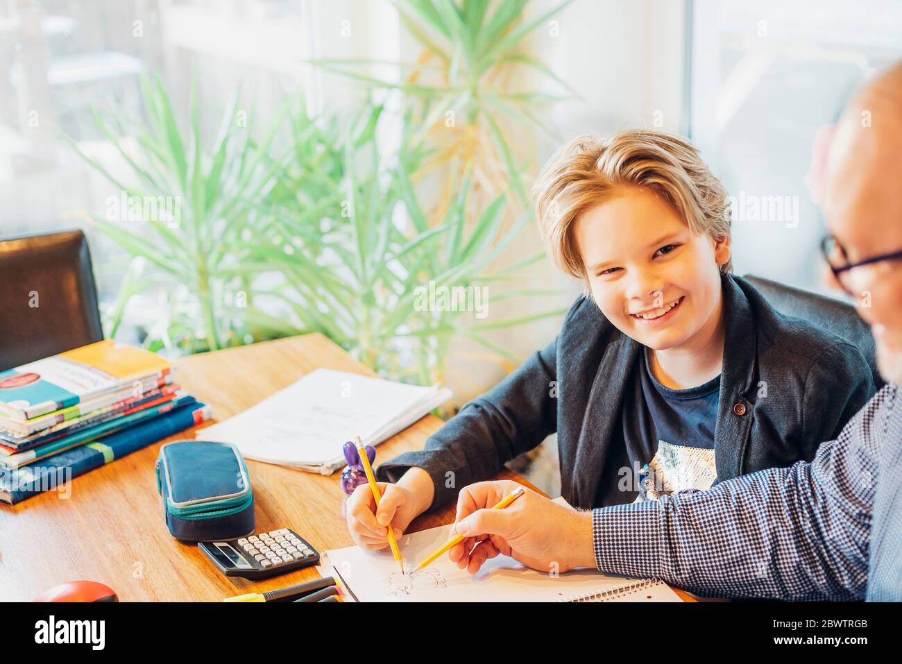 Smiling boy doing homework hi-res stock photography and images - Alamy