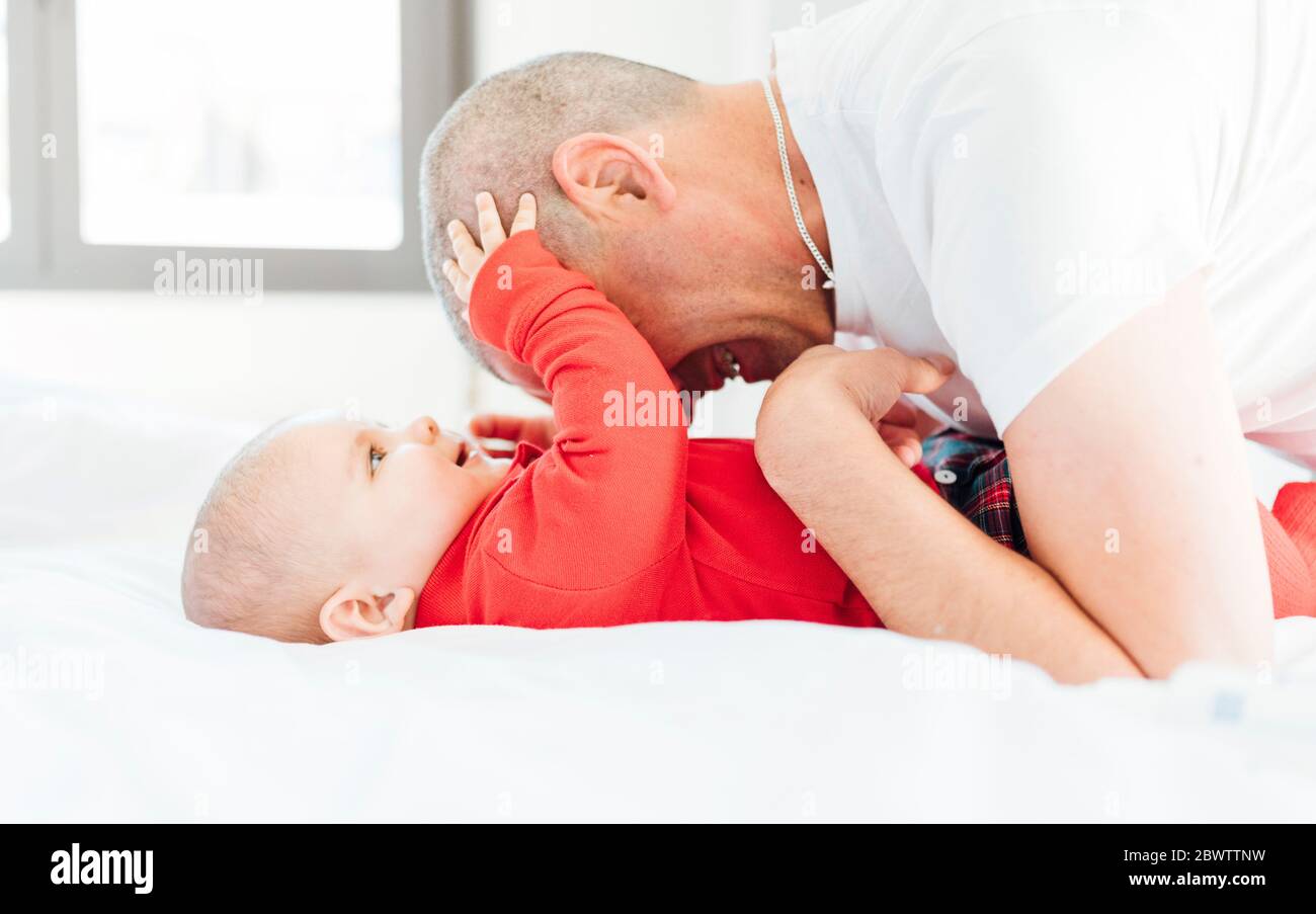 Fascinated baby boy touching father's shaved head Stock Photo - Alamy