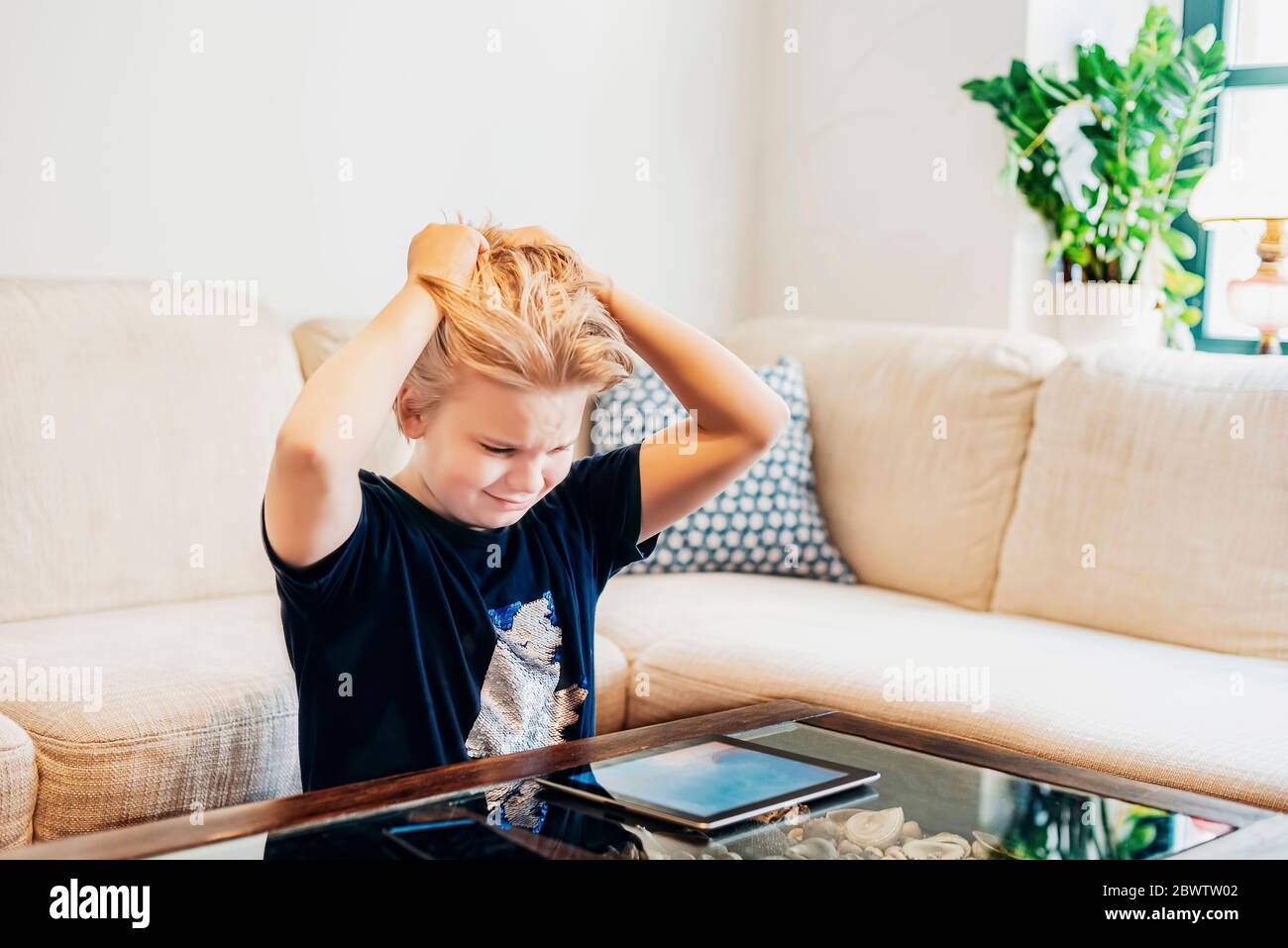 Frustrated boy with smartphone and tablet in living room Stock Photo ...