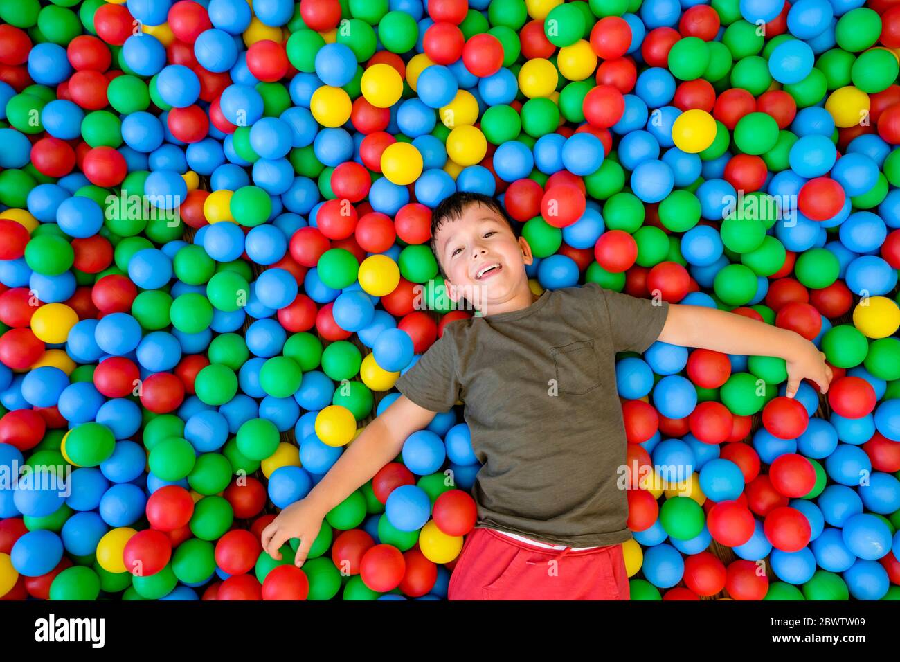 Smiling boy lying in ball pit Stock Photo - Alamy