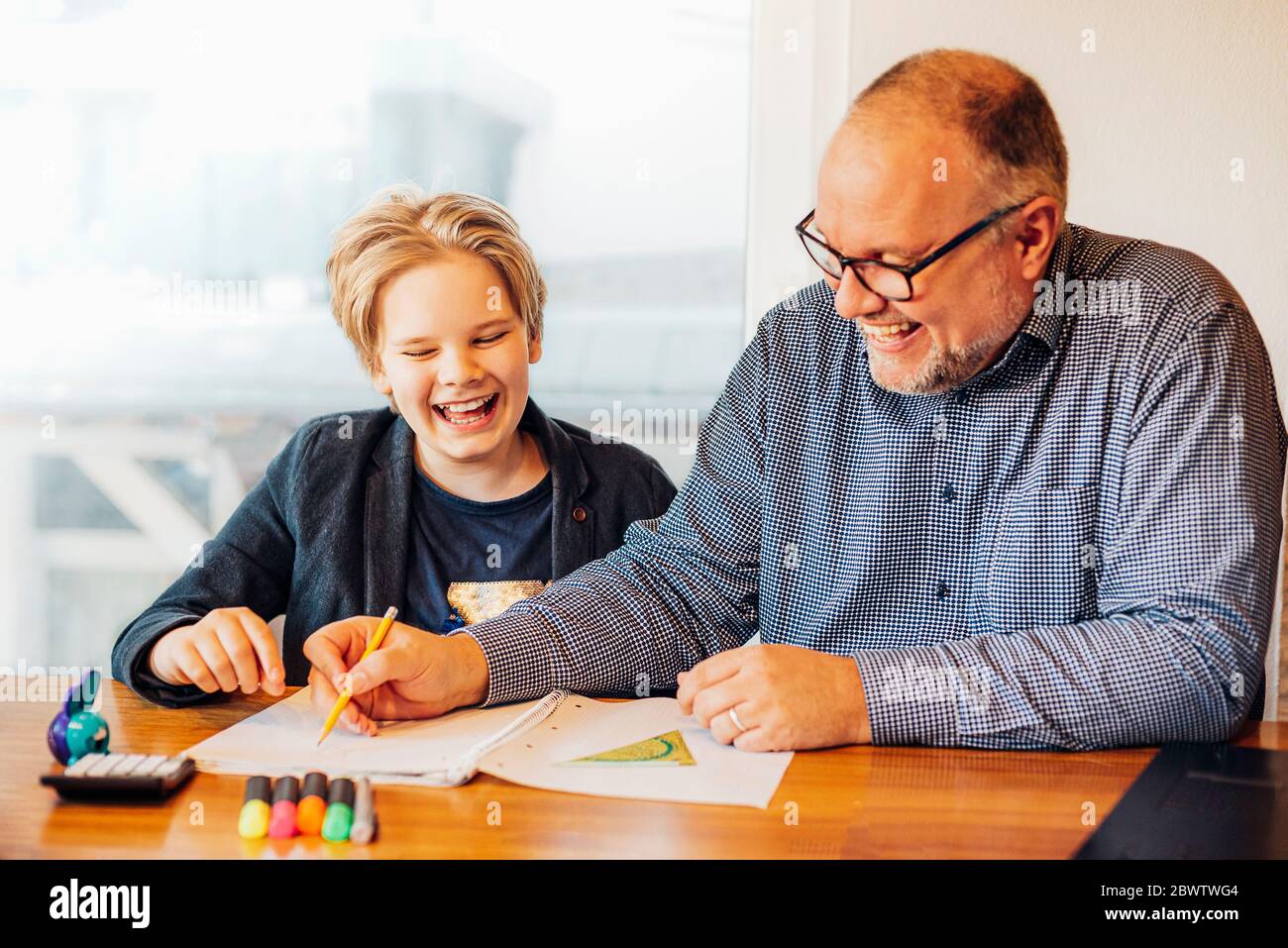 Happy father and son doing homework at desk Stock Photo - Alamy